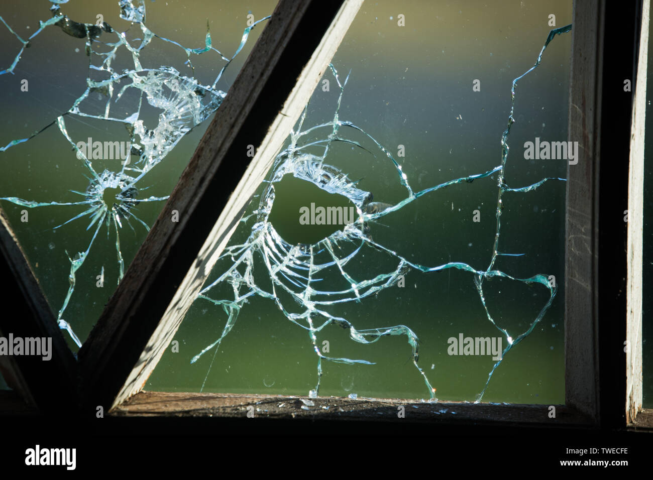 cracked and broken window glass punched by a pistol bullet Stock Photo ...
