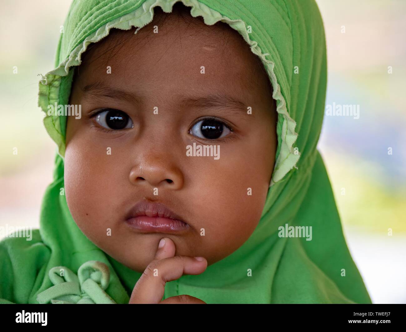 Little Indonesian girl with headscarf looks thoughtful, portrait, Java ...