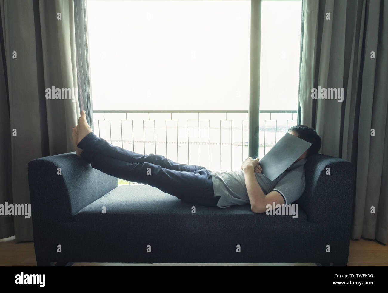 Man resting relax on modern sofa beside window Stock Photo - Alamy