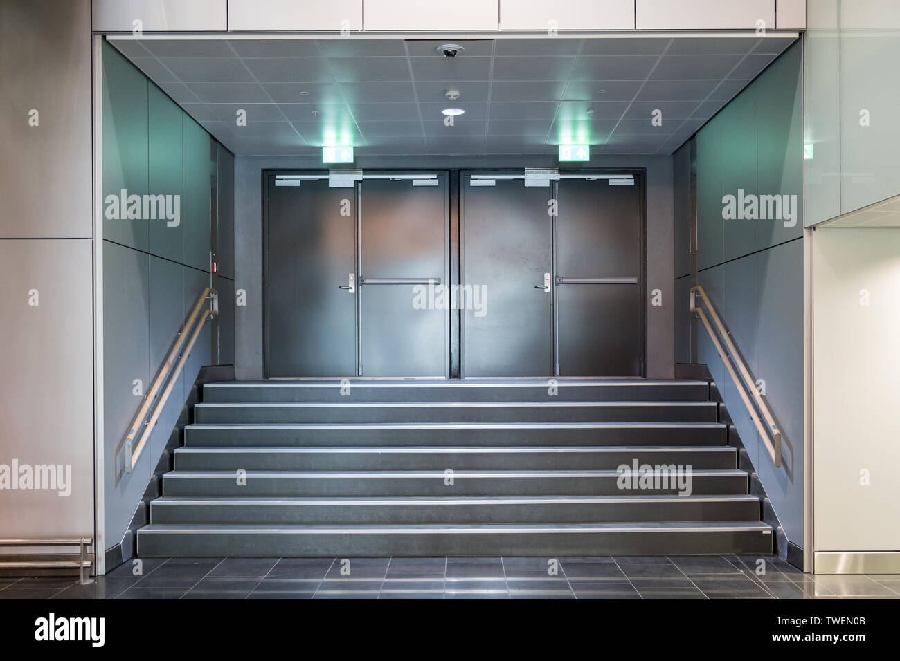 Fire exit metallic doors with staircase and handrails Stock Photo - Alamy