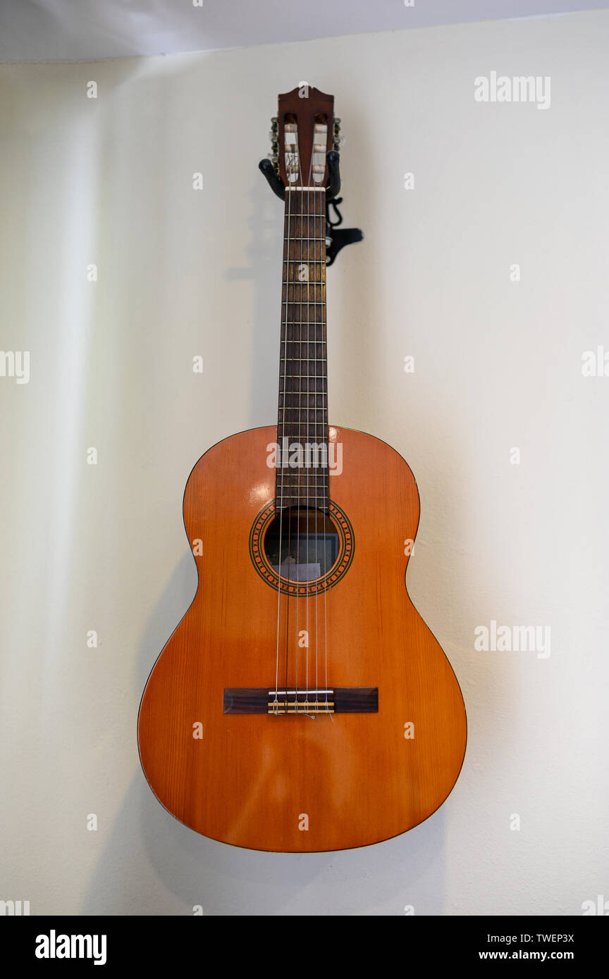 Brown acoustic guitar hanging decorative on wall Stock Photo - Alamy