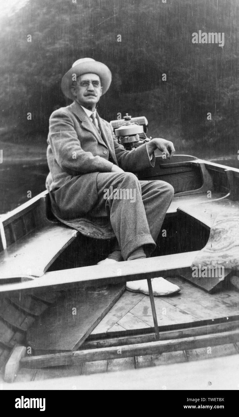 1930s photograph of a man in a boat with a small outboard motor ...
