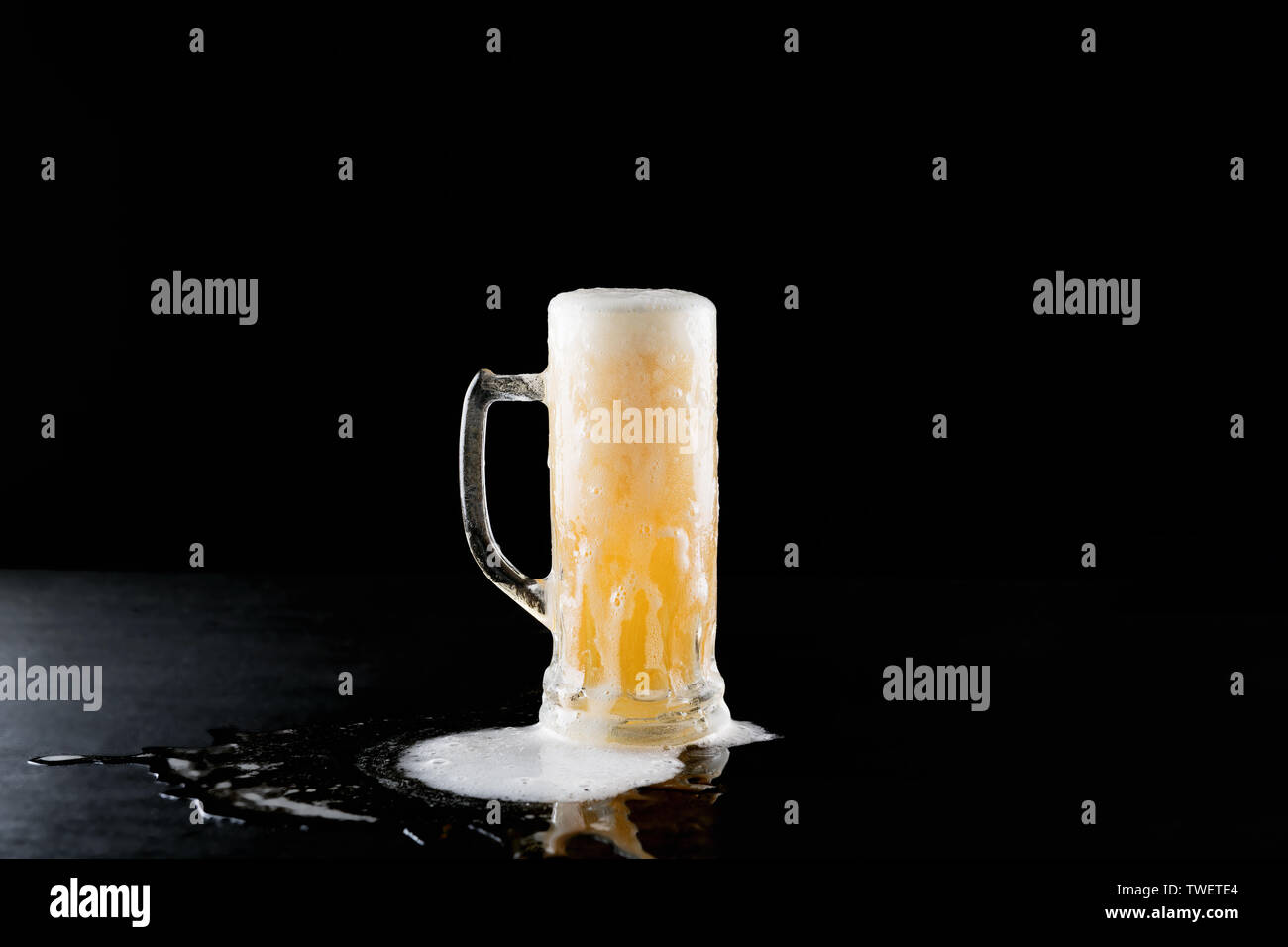 Cold Craft light lager beer in a overflowing mug with water drops with ...