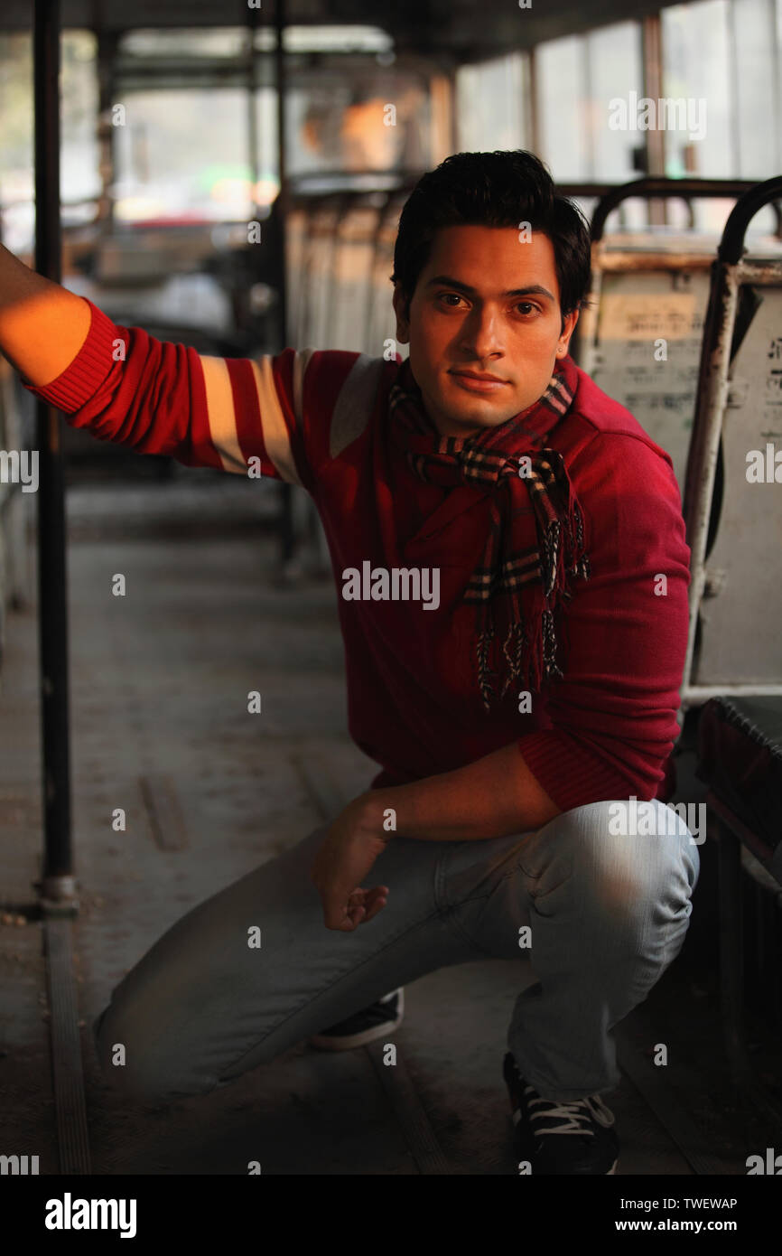 Portrait of an Indian young man crouching in a bus Stock Photo - Alamy