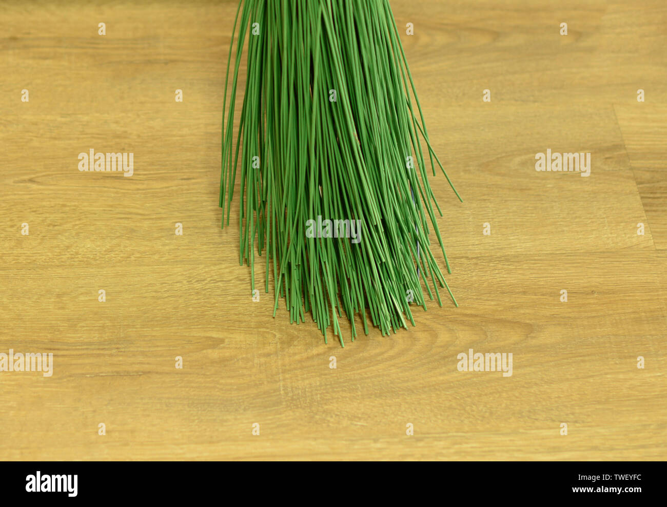 Long green plastic rods broom on the floor background with wooden ...
