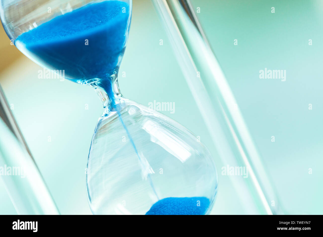 Time passing. Blue hourglass Stock Photo - Alamy