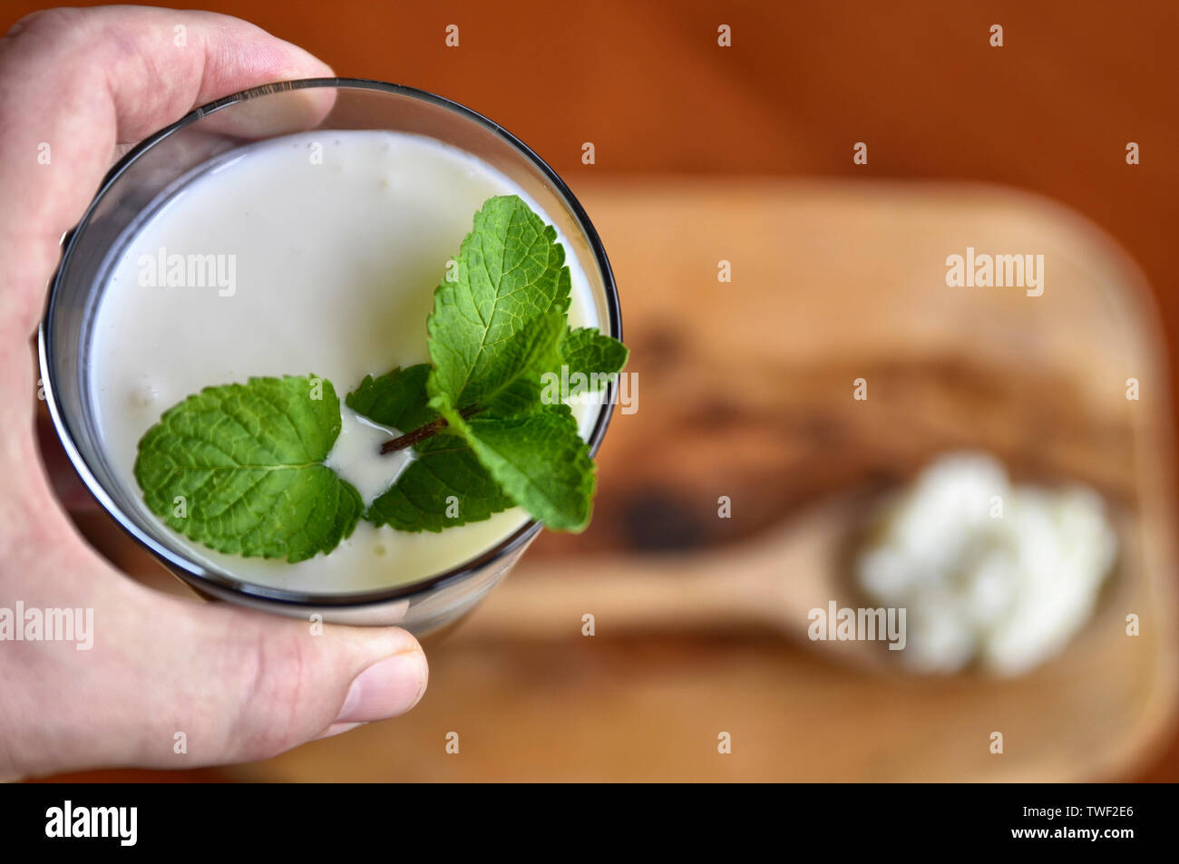 Close up shot of a glass full of kefir with mint leaves, in the blurred ...