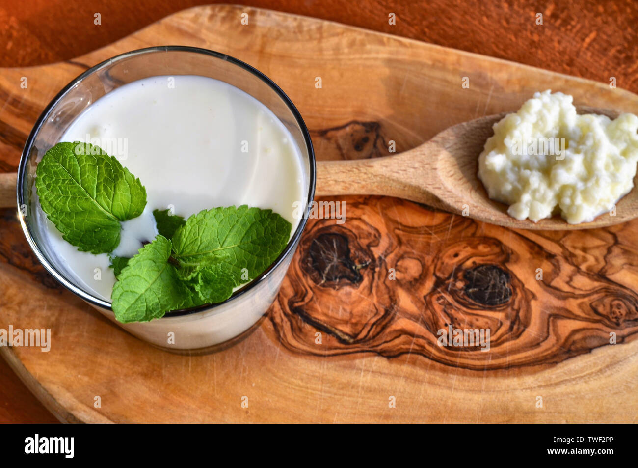 Close-up shot on a full glass of white Kefir enriched with some mint ...