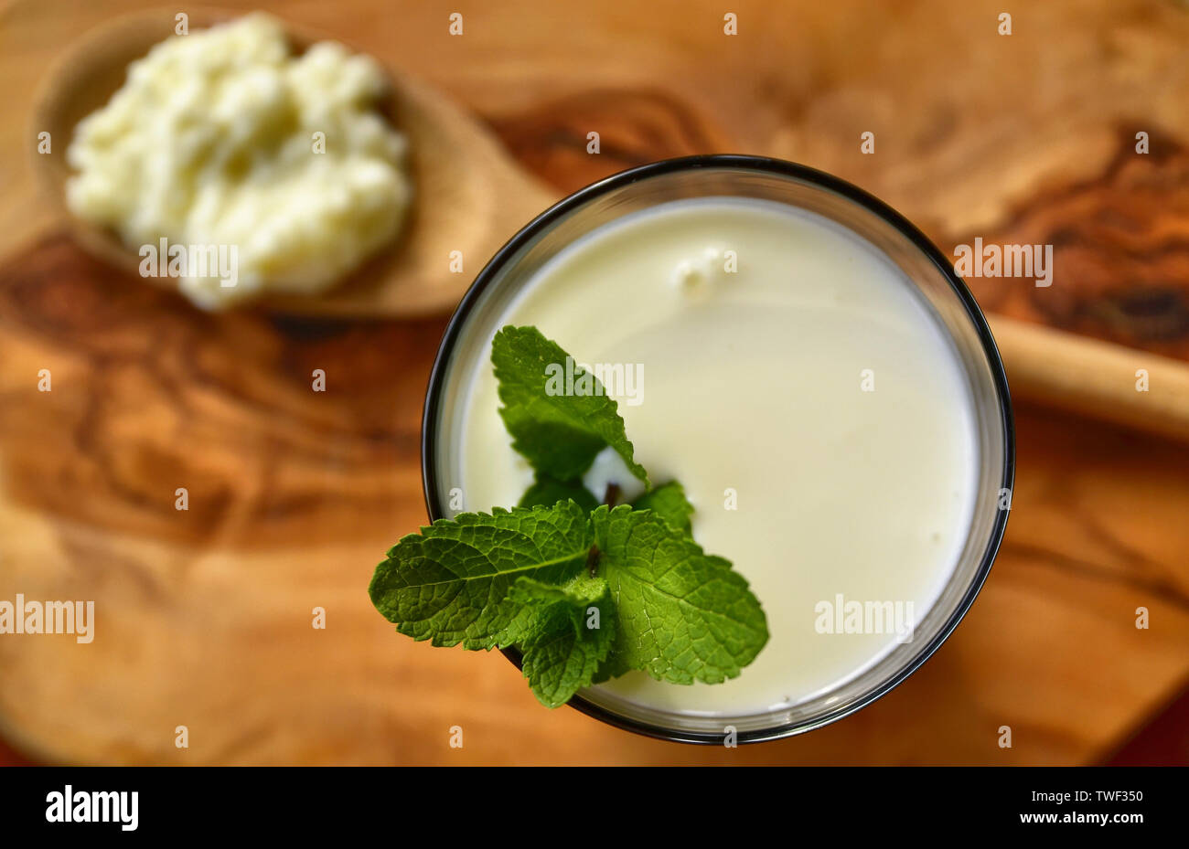 Close-up shot on a full glass of white Kefir enriched with some mint ...