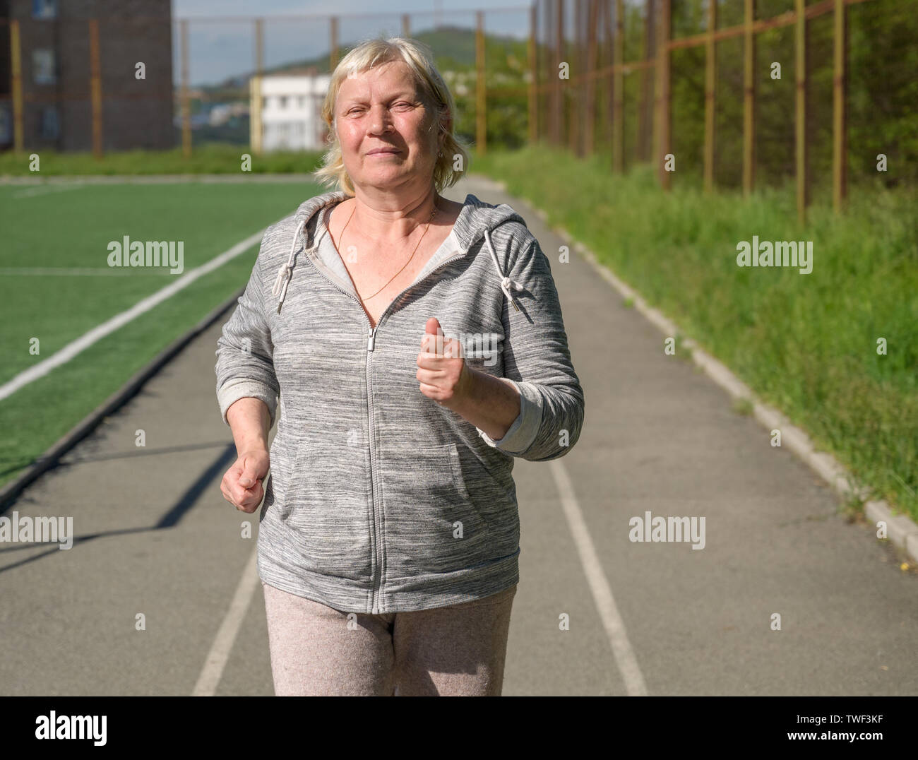 Aged woman jogging in public stadium Stock Photo - Alamy
