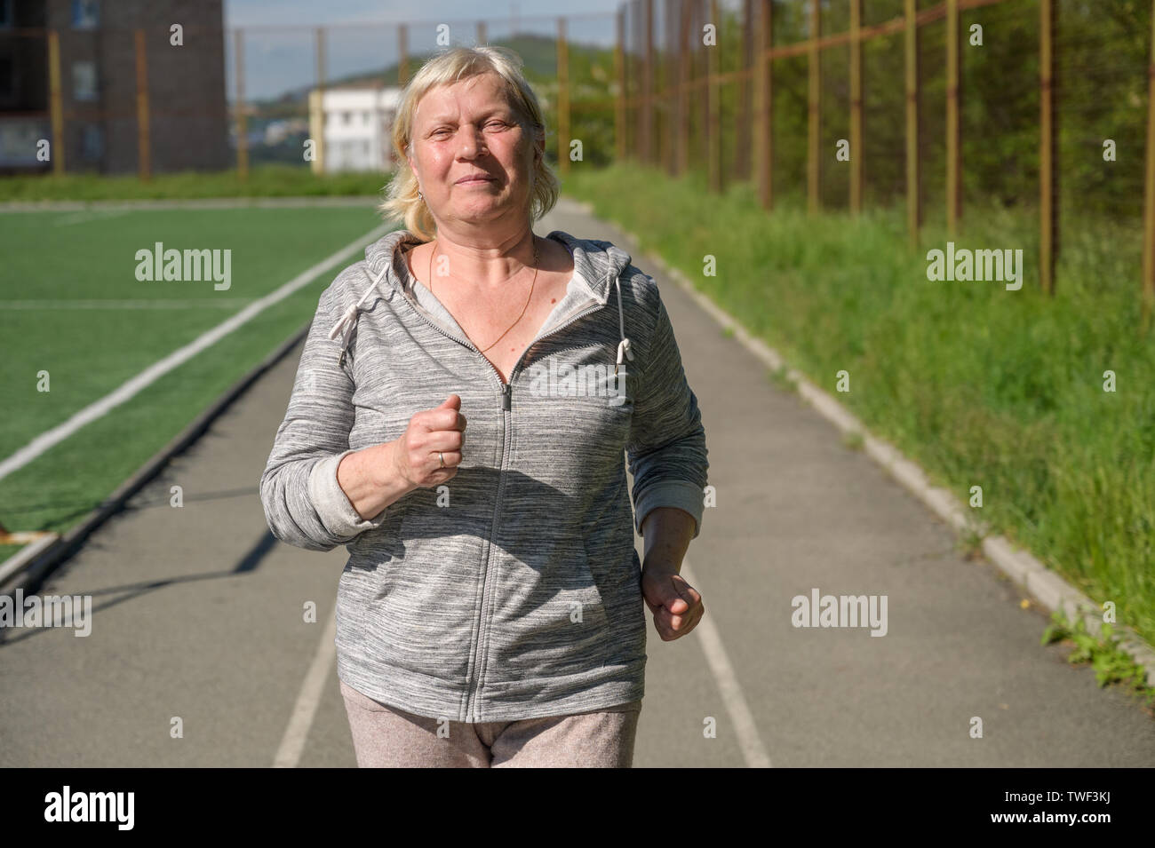 Aged woman jogging in public stadium Stock Photo - Alamy