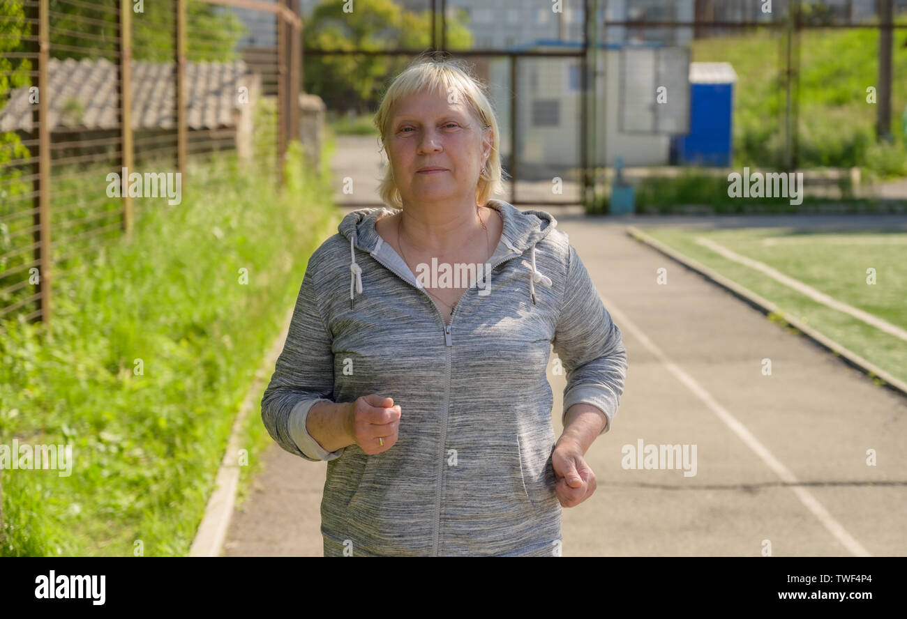 Aged woman jogging in public stadium Stock Photo - Alamy