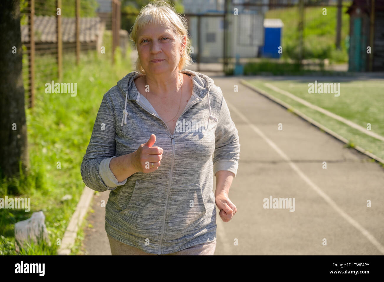 Aged woman jogging in public stadium Stock Photo - Alamy