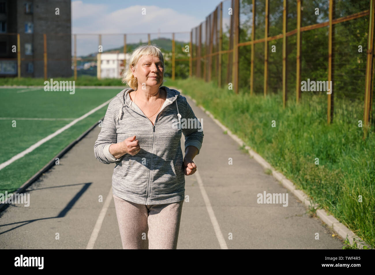 Aged woman jogging in public stadium Stock Photo - Alamy