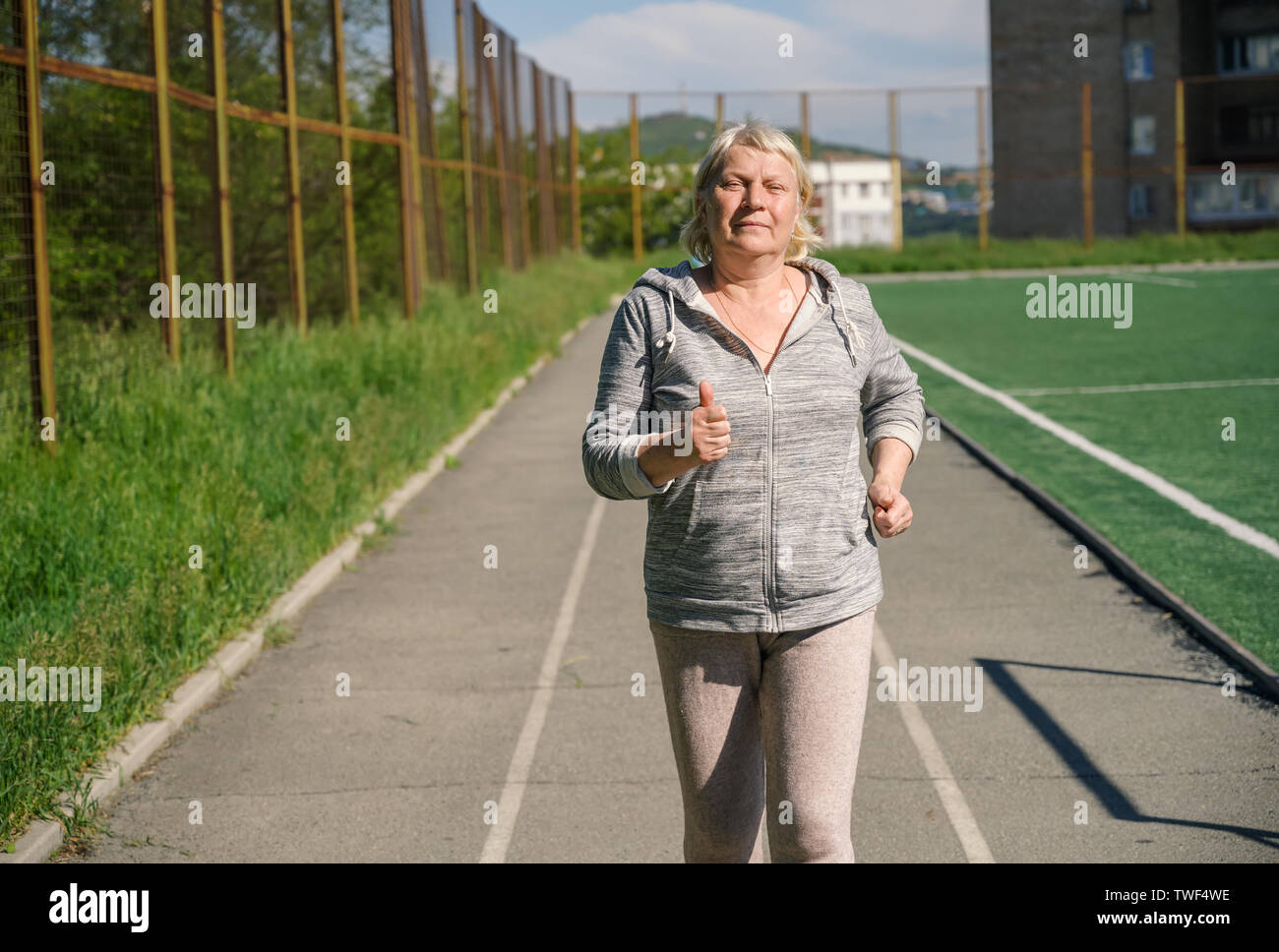 Aged woman jogging in public stadium Stock Photo - Alamy