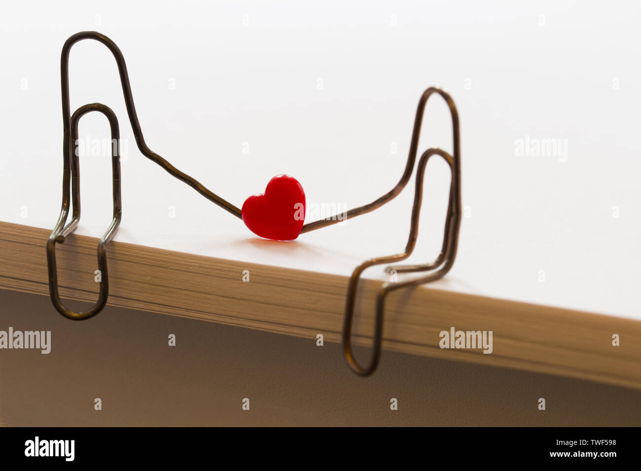 paper clips with heart symbolizing a person sitting on a stack of white ...