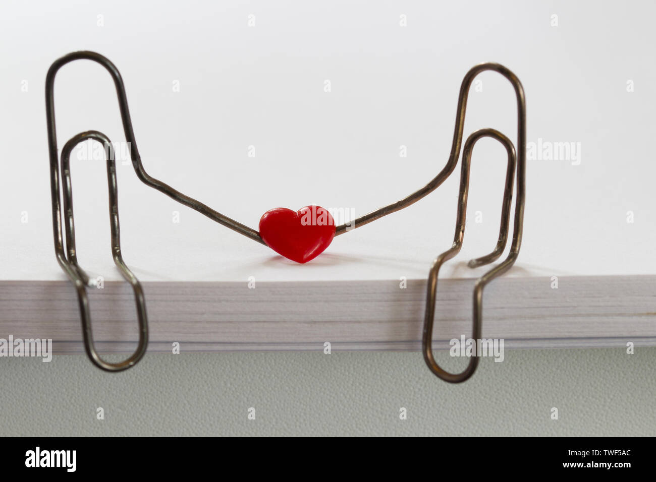 paper clips with heart symbolizing a person sitting on a stack of white ...