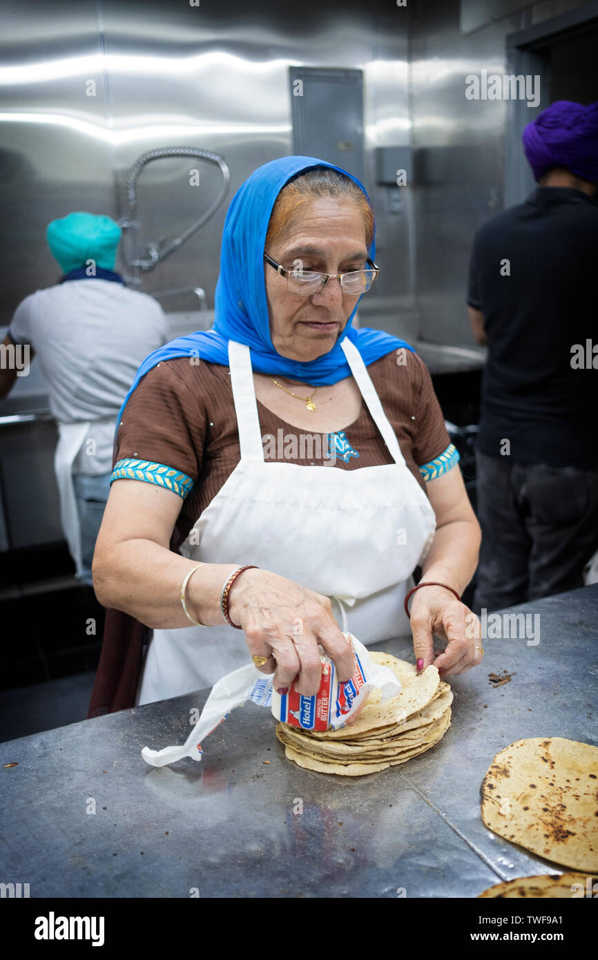 An older Sikh woman volunteer makes roti bread in the langar the The ...
