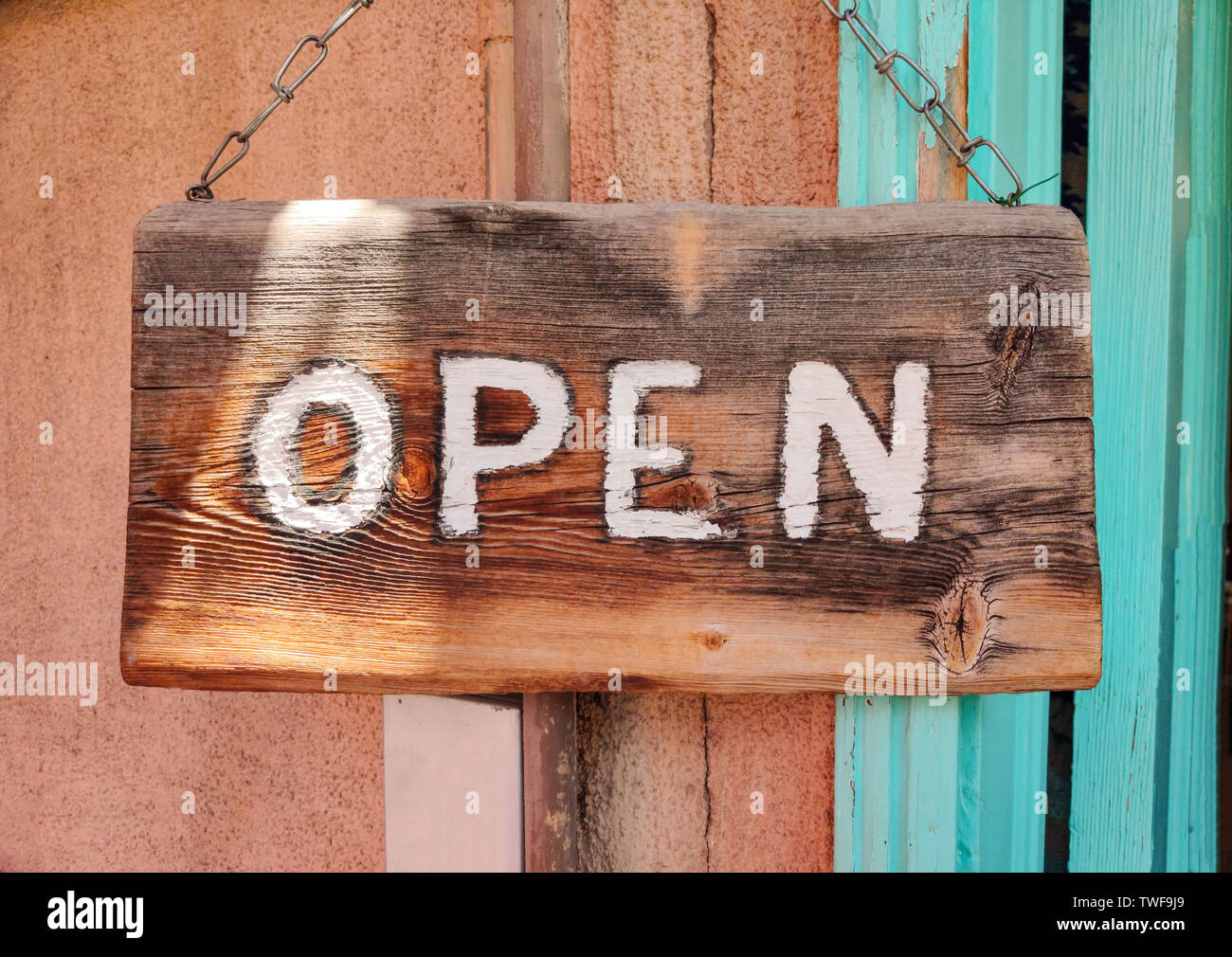 Open text on wooden sign board hanged with a metal chain on a buildings ...