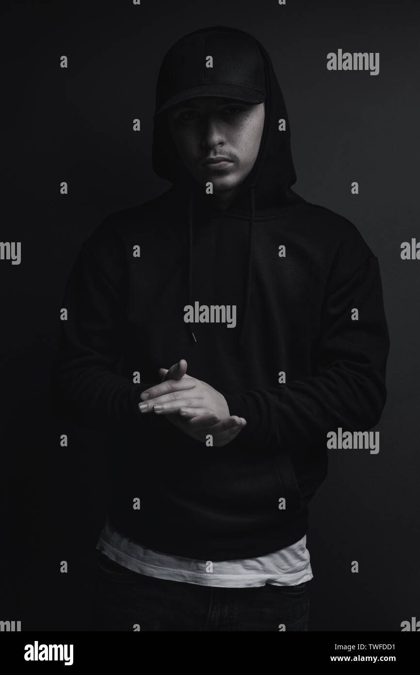 young cool rapper with black hoodie and cap clap his hands in front of ...