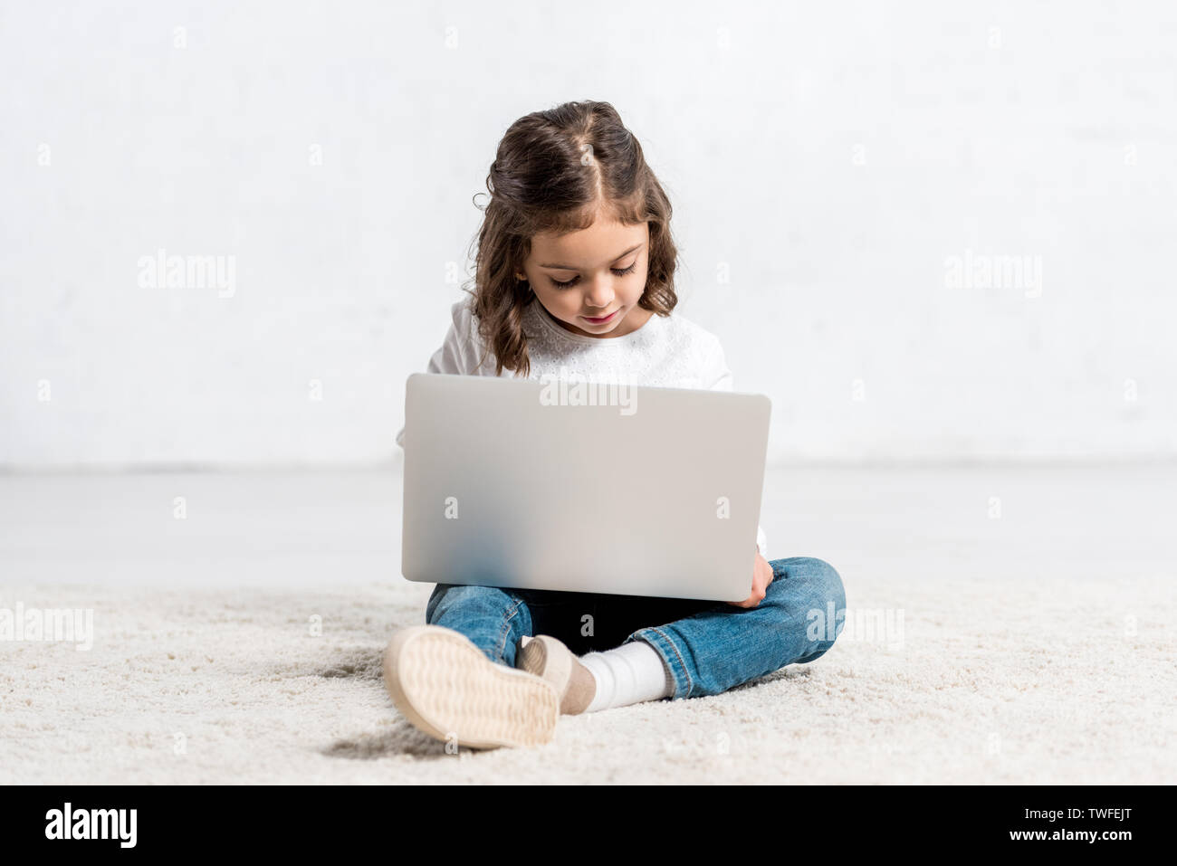 Concentrated preschooler kid using laptop while sitting on floor on ...