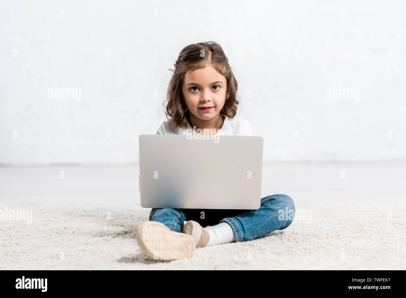 Adorable kid sitting on floor and using laptop on white Stock Photo - Alamy