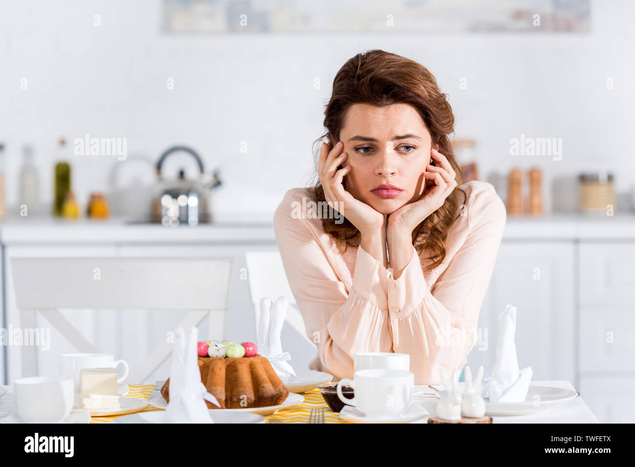 Upset woman sitting and the table with easter cake and propping face ...