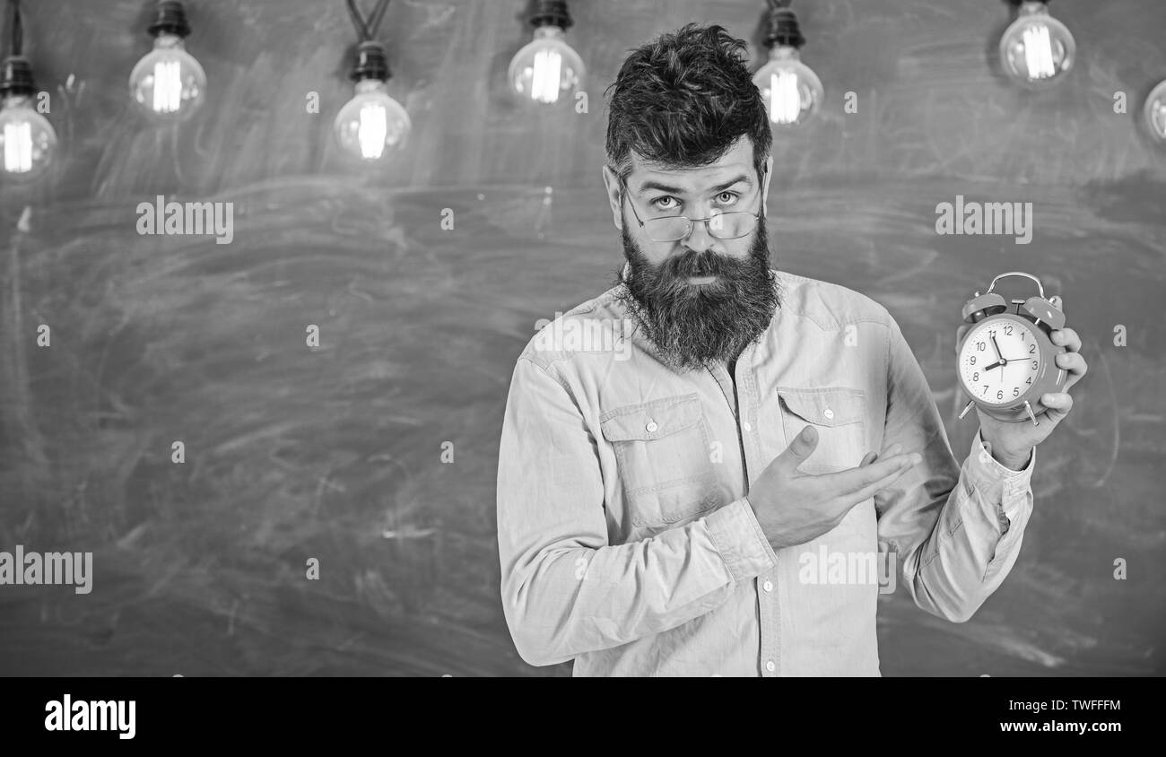 Teacher in eyeglasses holds alarm clock. Discipline concept. Man with ...