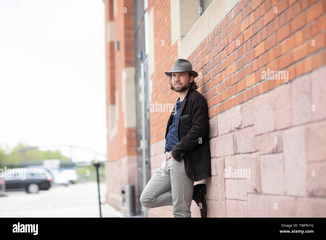 Portrait of a man leaning against a wall Stock Photo - Alamy