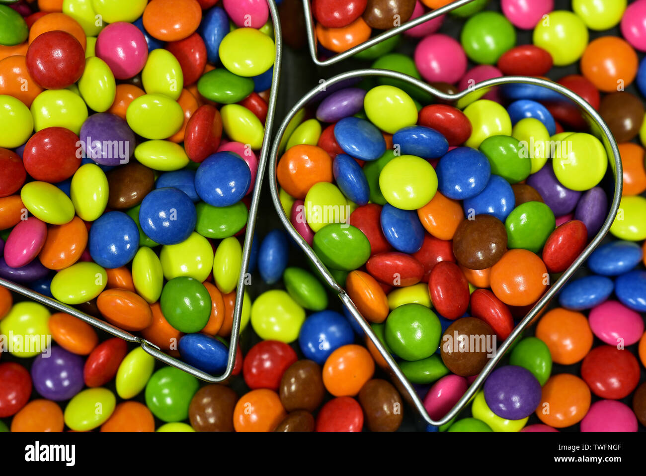 colorful little chocolate dragees amidst hearts of metal Stock Photo ...