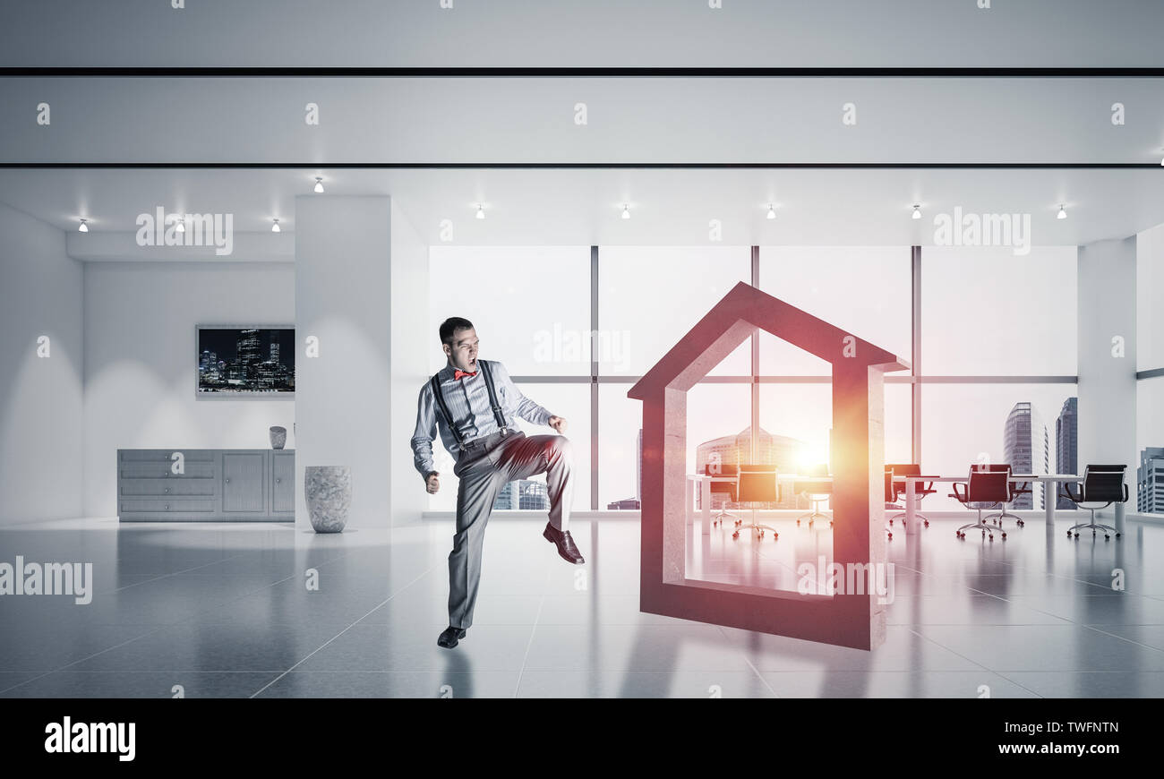 Determined businessman going to break with kick house concrete figure ...