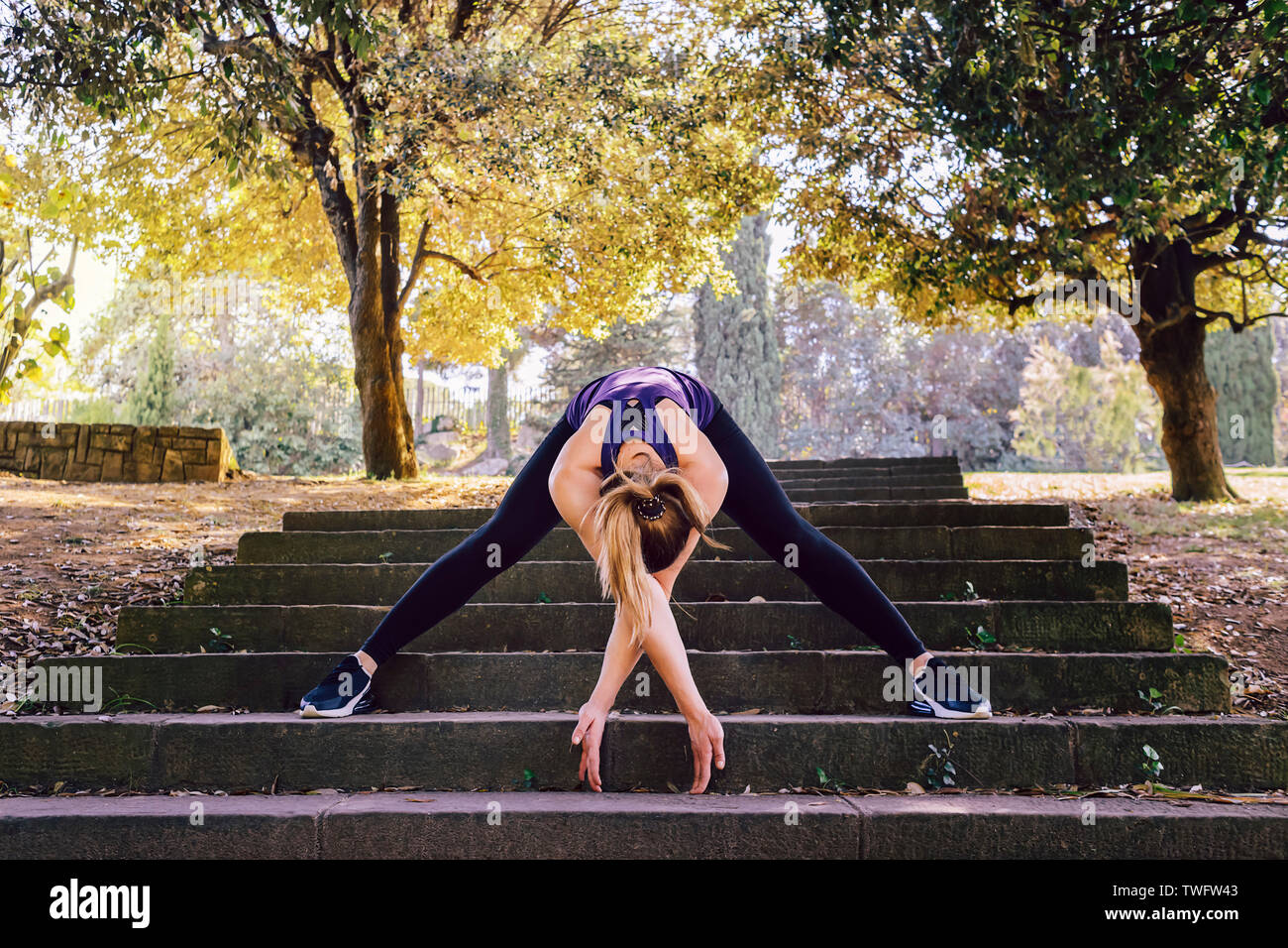 young girl runner doing some warm up exercises and stretching legs ...