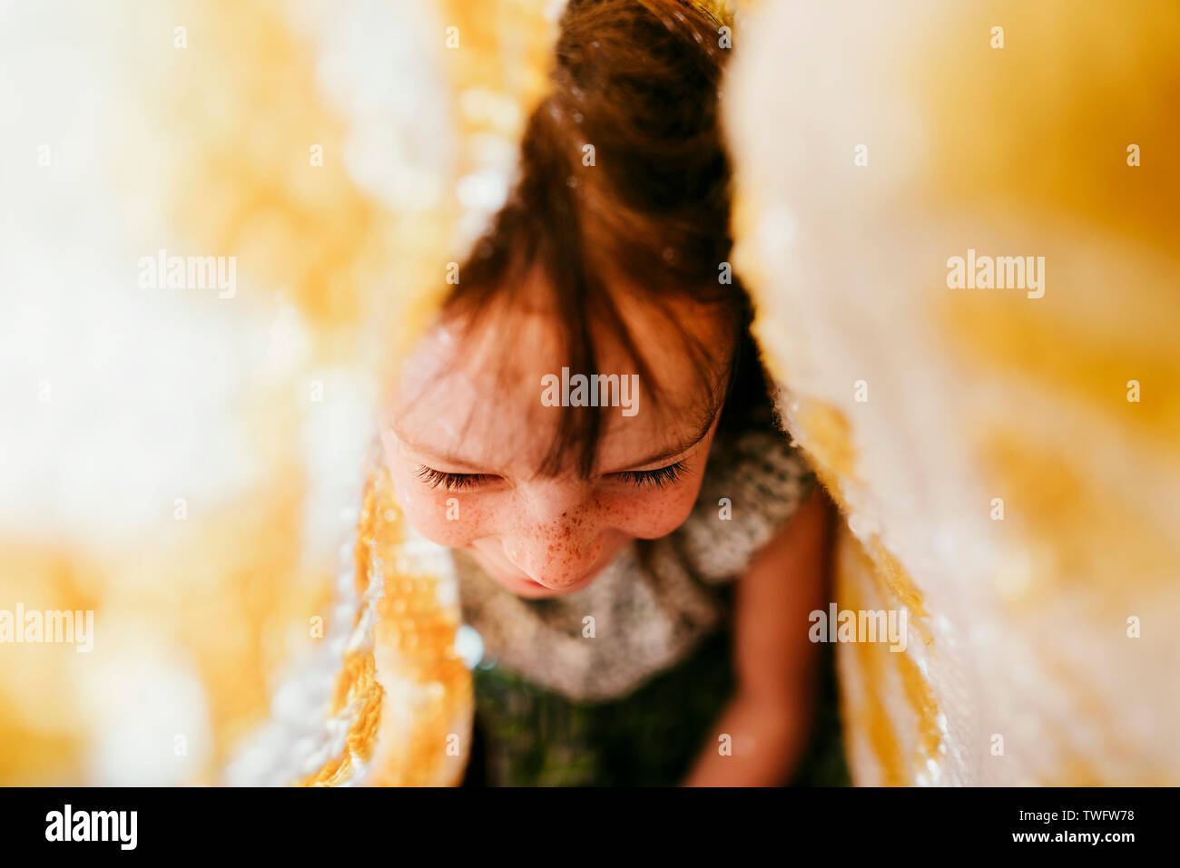 Portrait of a girl hiding under a blanket laughing Stock Photo - Alamy