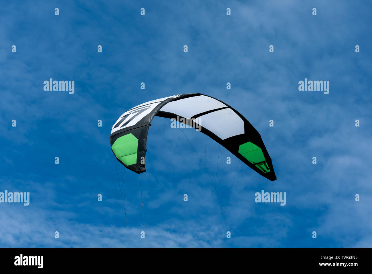 White and green kitesurfing towing kite in the air with a blue sky as ...