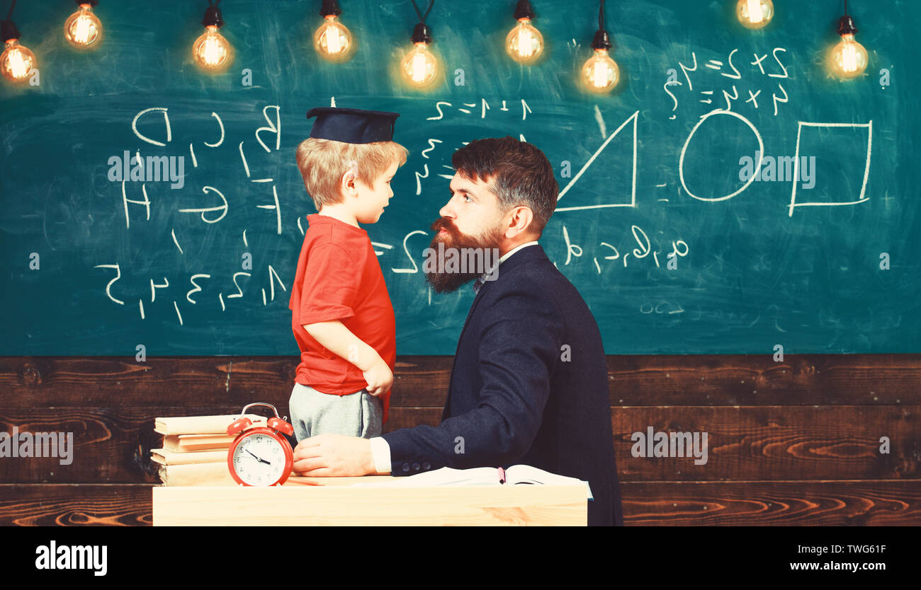 Teacher with beard, father teaches little son in classroom, chalkboard ...