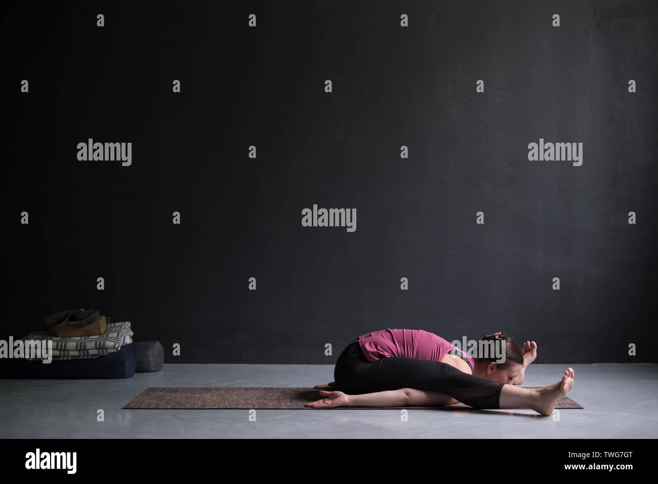 Young woman practicing yoga, doing Kurmasana, Tortoise posture, Turtle ...