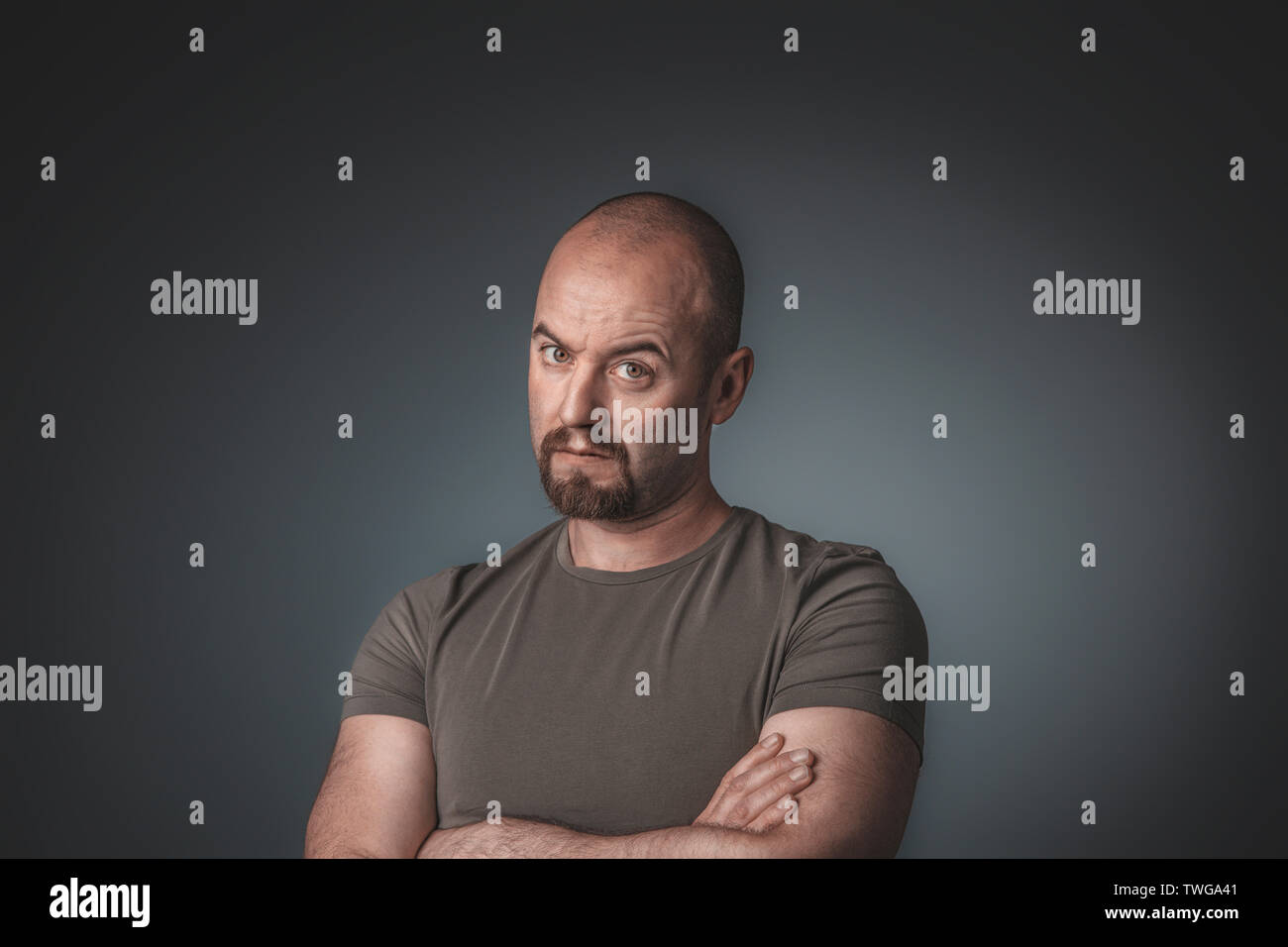 studio portrait of man with doubtful expression and arms crossed ...