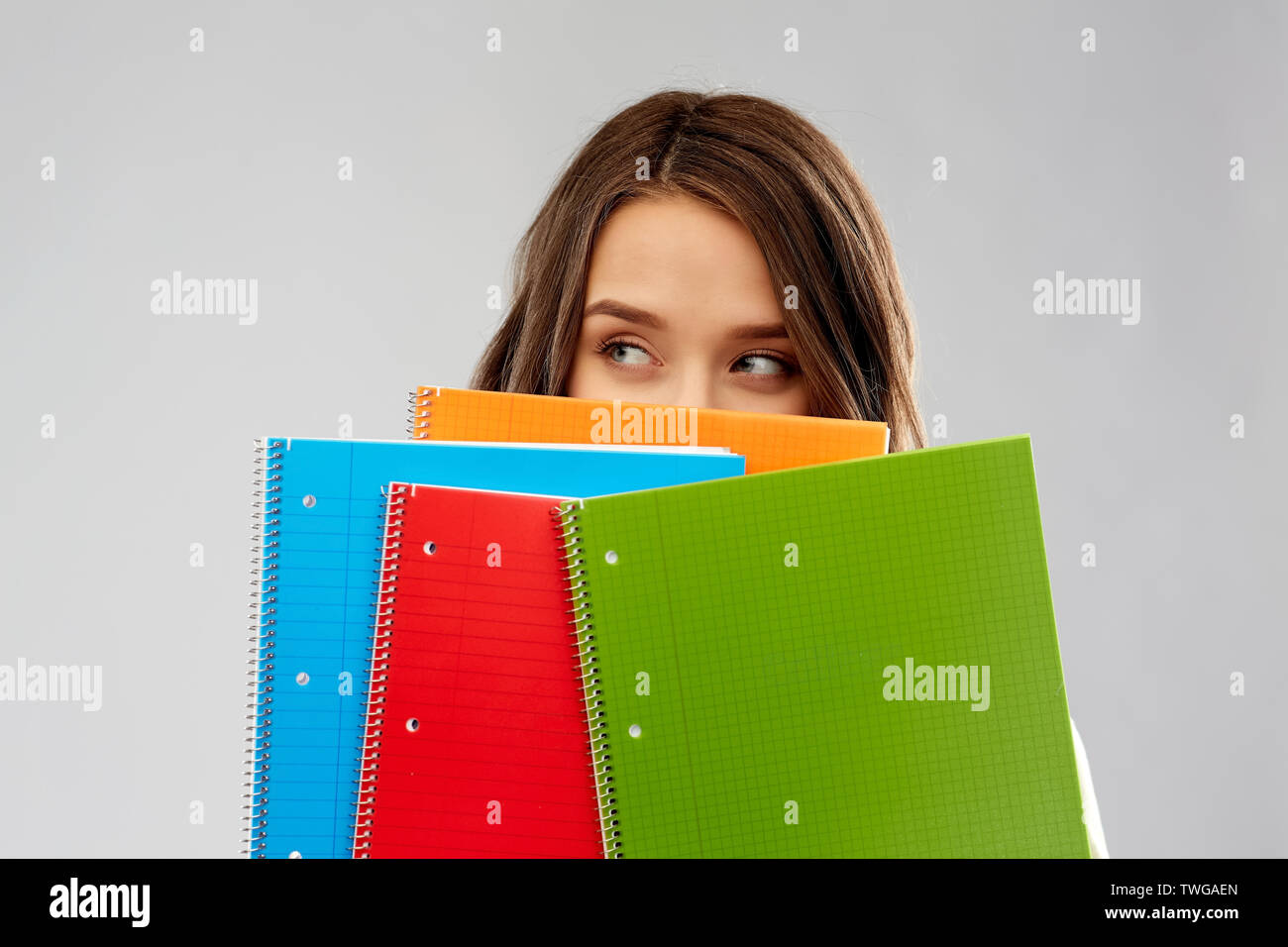 teenage student girl hiding behind notebooks Stock Photo - Alamy