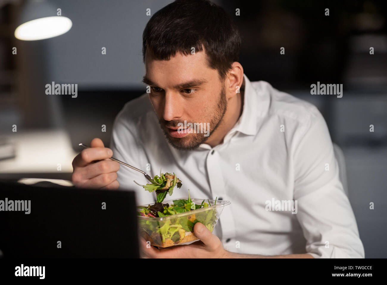 businessman with computer eating at night office Stock Photo - Alamy
