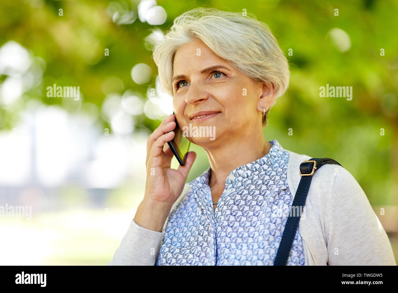 senior woman calling on smartphone in summer park Stock Photo - Alamy