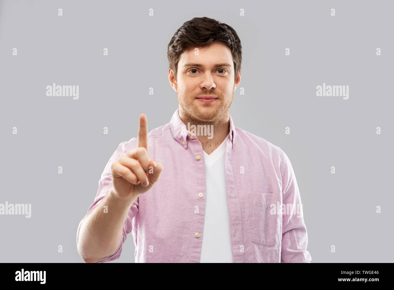 young man showing one finger over grey background Stock Photo - Alamy
