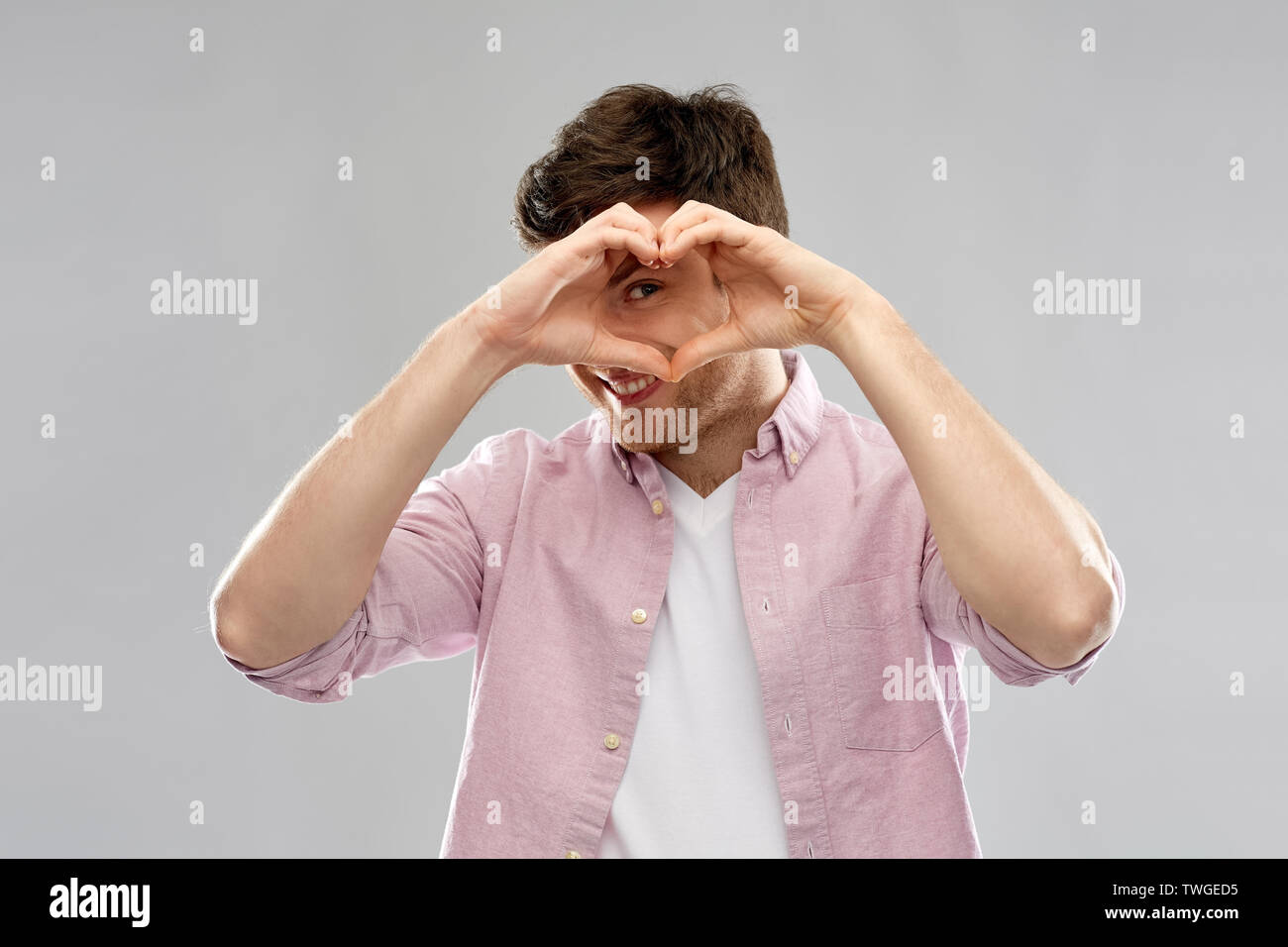 man making hand heart gesture over grey background Stock Photo - Alamy