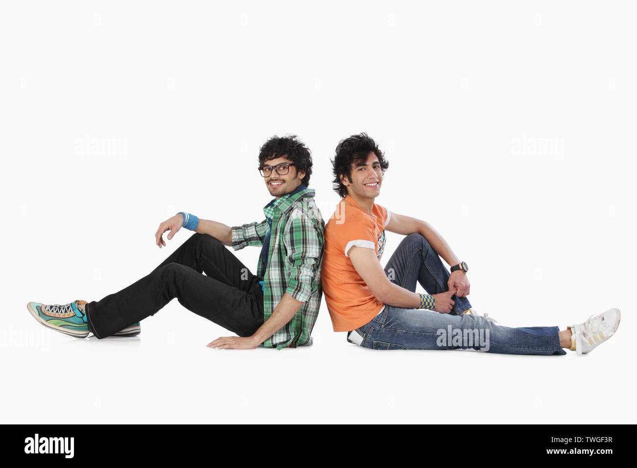 Two friends sitting back to back and smiling Stock Photo - Alamy