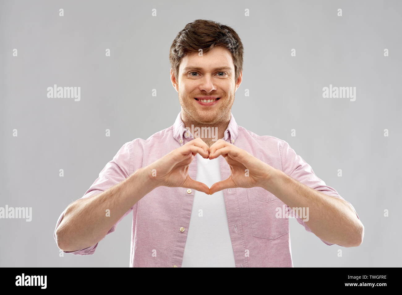 man making hand heart gesture over gey background Stock Photo - Alamy