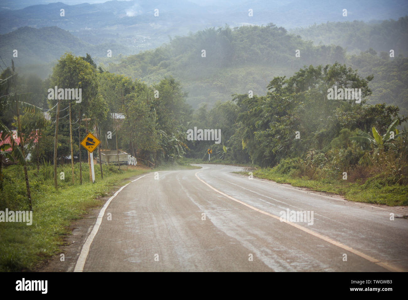 Rain falling drive with caution traffic alerts downhill slope. Reduce ...