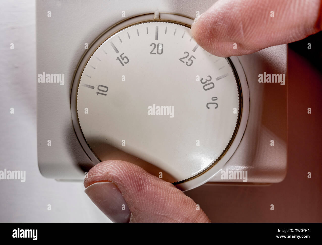 Mans fingers setting the rotary control of a central heating system ...