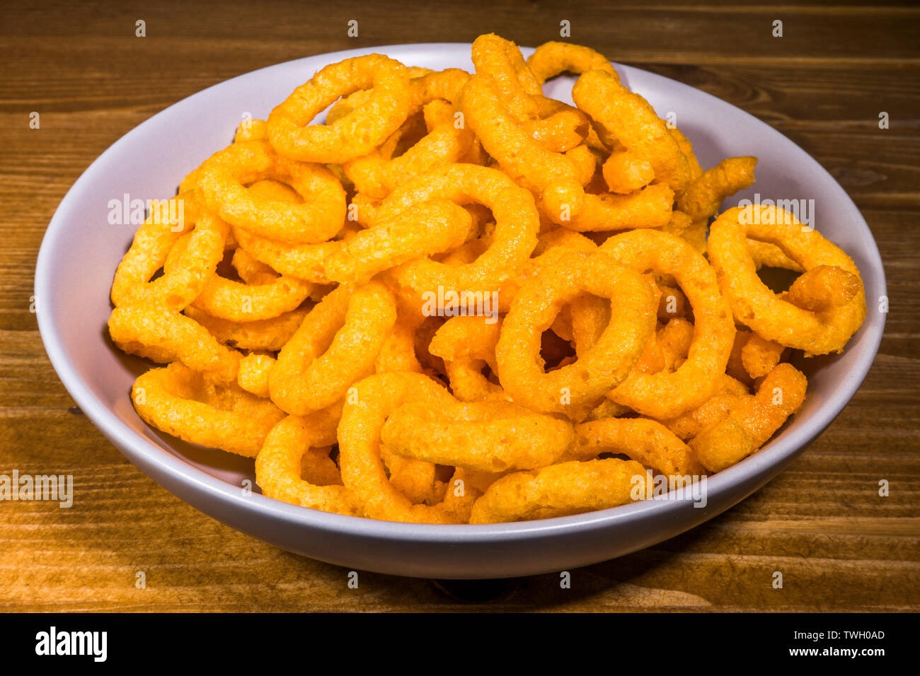 Onion rings shape and flavour, crispy corn snack, piled up in a bowl on ...