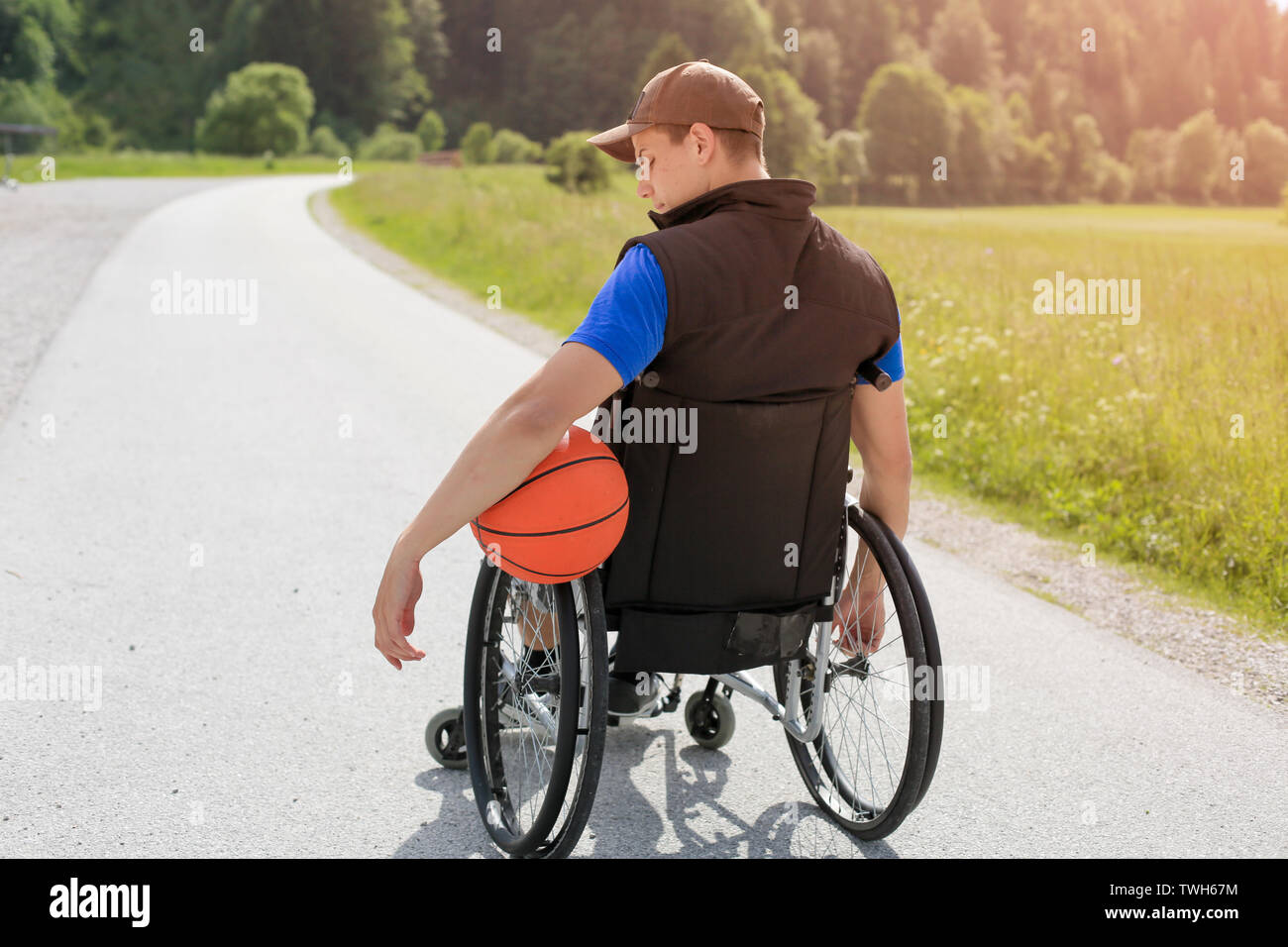 Disabled young basketball player on a wheelchair holding ball and ...