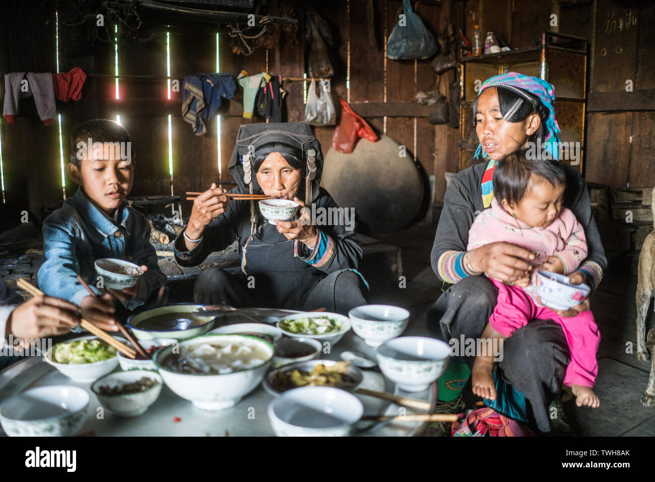 women Akha Pixor ethnicity and their childrens have lunch in the kitchen, Phongsali, Laos, Asia ...