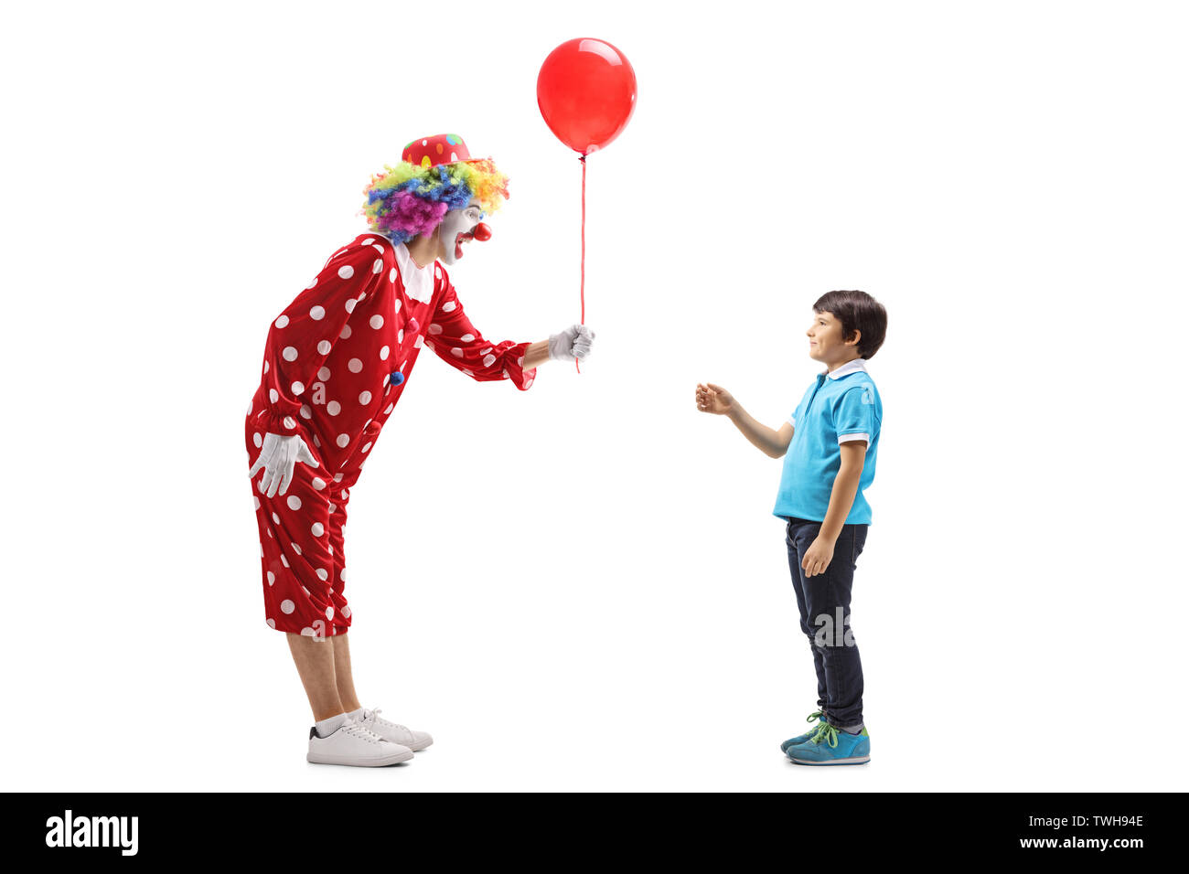 Full length profile shot of a clown giving a red balloon to a boy ...